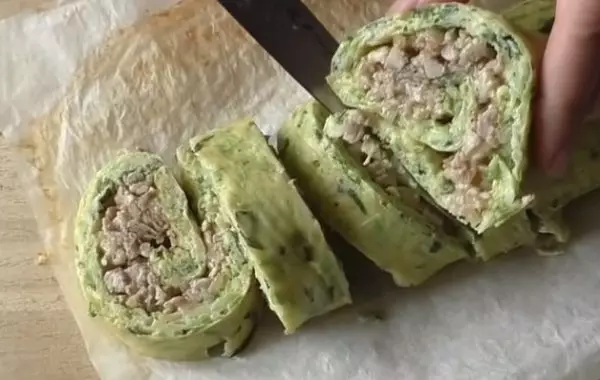 Rodajas por rebanadas de porciones Zucchini Roll con carne picada en una hoja de papel para hornear