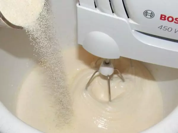 एक मिक्सर कटोरे में चीनी-अंडे के मिश्रण में सेमोलिना जोड़ना