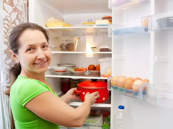 Wanita menempatkan wajan panas di lemari es
