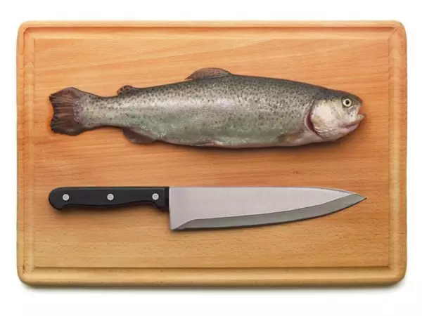 Ikan pada papan memotong kayu dan pisau