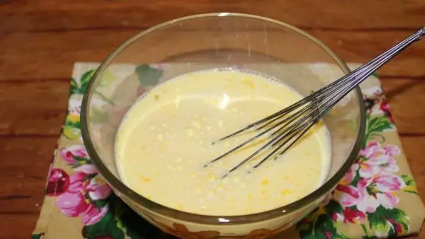 Blandning av ägg och mjölk i en glasskål med metallisk kil