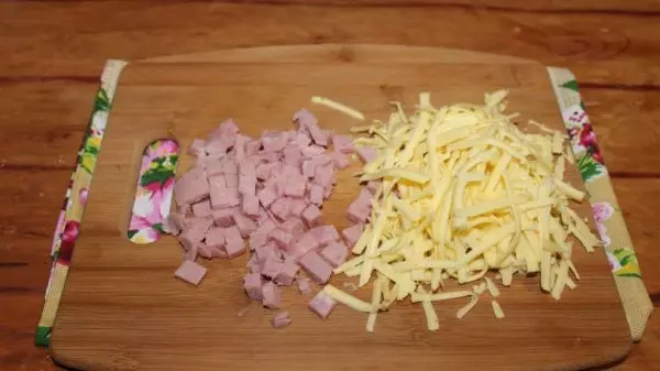 Prosciutto a fette e formaggio solido grattugiato su un tagliere