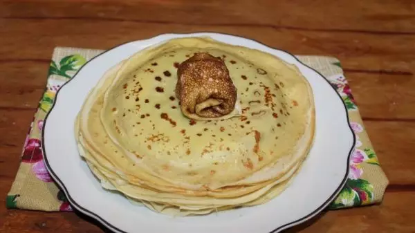 Pila di semplici pancake e pancake con riempimento sotto forma di un rotolo