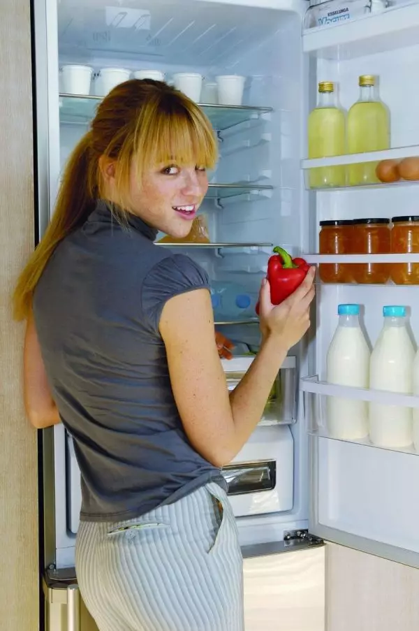 Rapaza no frigorífico aberto