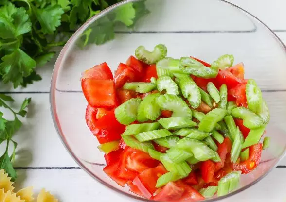 Tranĉaĵaj tomatoj, bulgara pipro kaj celerio en vitra bovlo