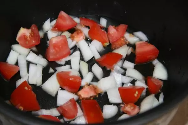 Нарізані шматочками свіжі помідори і ріпчасту цибулю в чаші мультиварки