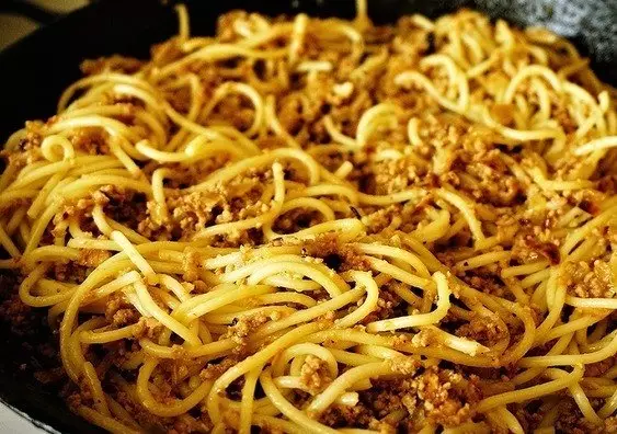 Boiled spaghetti with minced meat in a frying pan