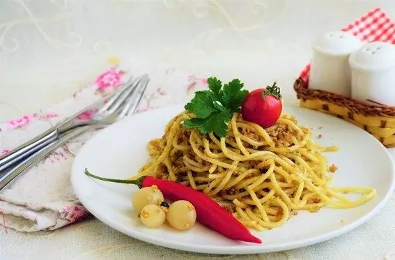 Spaghetti with minced meat on a white plate served by vegetables