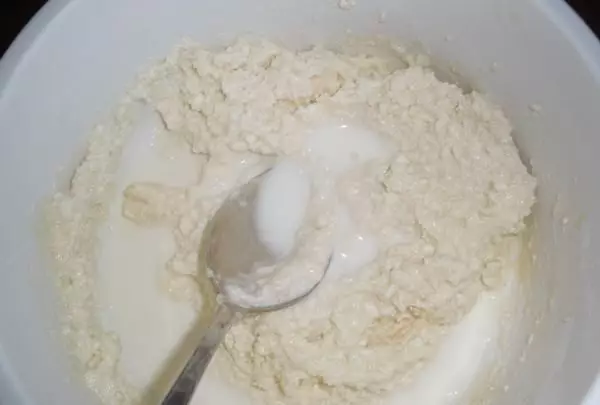 Cottage cheese with sugar and milk in a bowl with an iron spoon