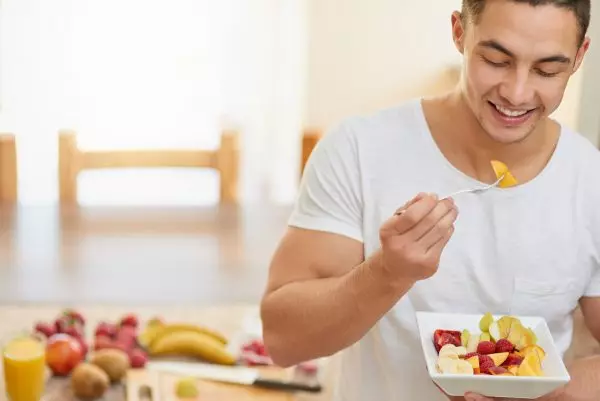 Un uomo mangia un'insalata di papaia e altri frutti