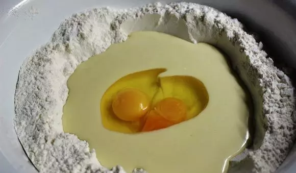 Campuran minyak dan telur mentah dalam mangkuk dengan tepung