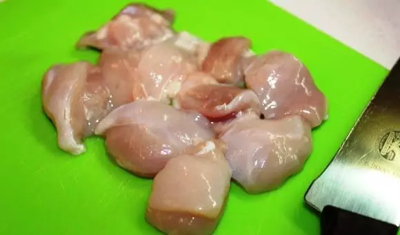 Ψιλοκομμένο με φέτες ακατέργαστο κρέας κοτόπουλου σε πράσινο πίνακα κοπής