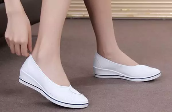 Бяла балетни обувки на женски крака