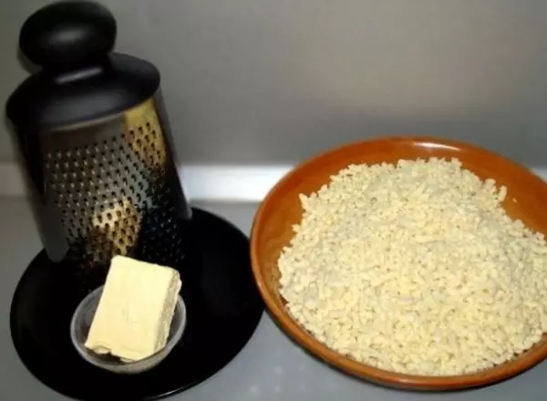 Faites défiler un fromage de meulement de viande dans un bol, une cale de chuste et du beurre de métal