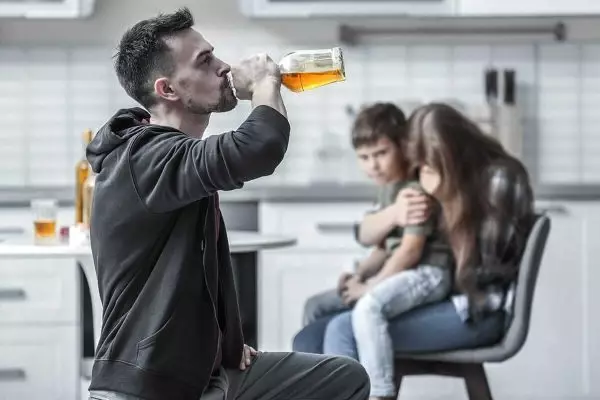 Muž pije před svou ženu a dítě