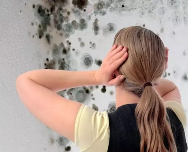 Femme tenant la tête à la vue d'un champignon sur les murs