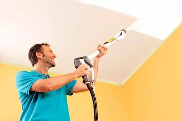 Un uomo dipinge il soffitto con spray