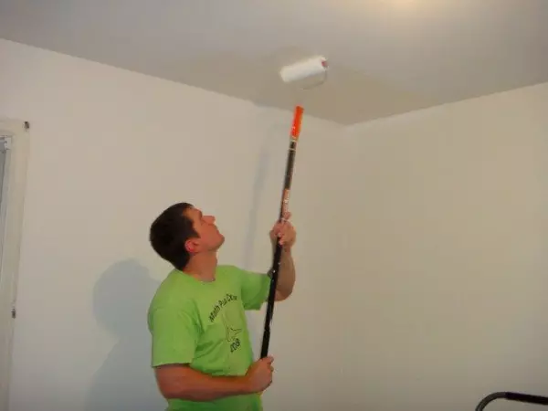 आदमी एक छत रोलर पेंट करता है