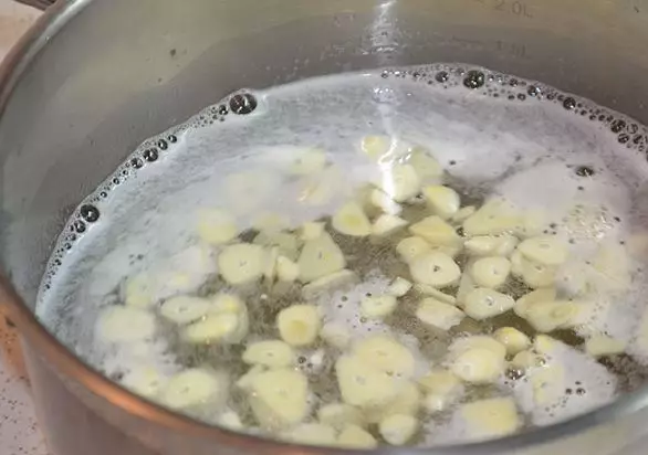 Slices of garlic in a metal saucepan with water
