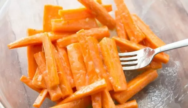 ตัดชิ้นแครอทในเนยละลายและส้อมโลหะ