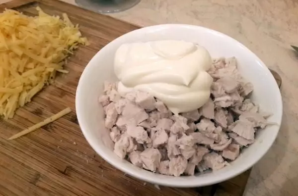 Poulet avec des cubes viande de poulet bouillie avec mayonnaise dans une assiette blanche sur une planche à découper