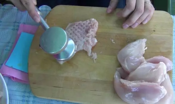 Kyllingfilet på en træplade og hammer til madlavningskoteletter