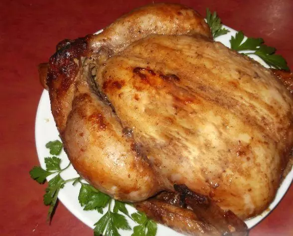 Pollo entero al horno con miel y mostaza en un plato blanco grande