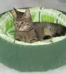 Кот в подвійній лежанці, де зовнішня частина - з зеленого флісу, а внутрішня - з світлого бавовни