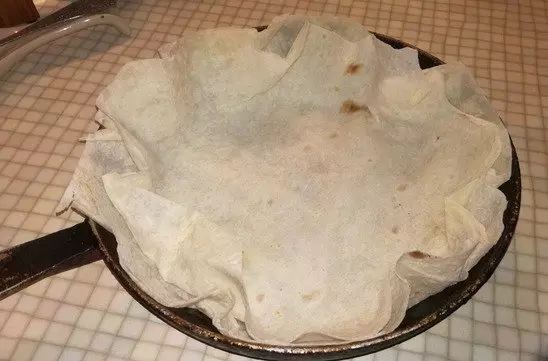Lavash sheet sa isang cast-iron frying pan sa talahanayan