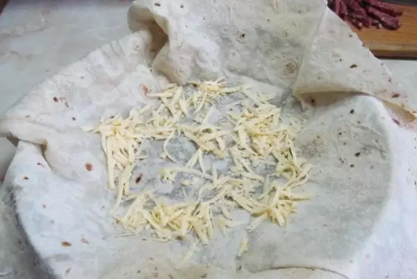 苗條皮塔餅和磨碎的固體奶酪在煎鍋中