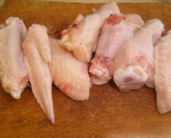 Rå kyllingevinger skåret på træ skærebræt