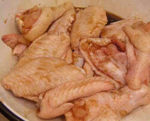 أجنحة الدجاج الخام في وعاء مع ماء مالح
