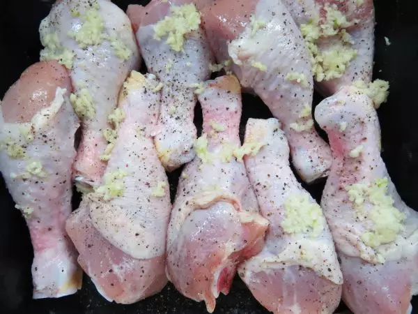 Сурови пилешки крака с нарязан чесън и черен пипер