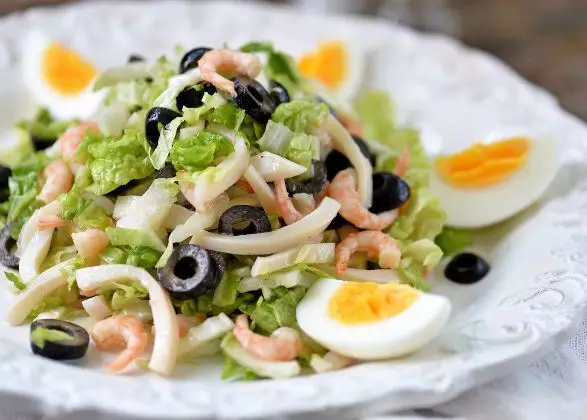 სალათი ერთად squid, ზეთისხილი და მოხარშული კვერცხები ლამაზი თეთრი ფირფიტა