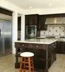 Острво стол у кухињи са тамно смеђим намештајем