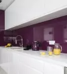 The combination of purple apron and white furniture in a small kitchen