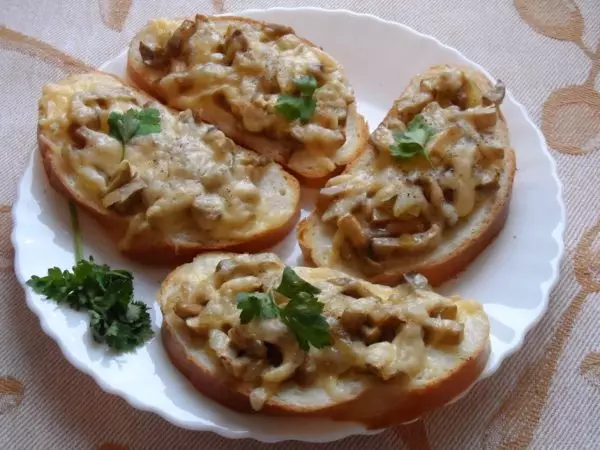 Klaar hete broodjes met champignons, kaas en greens op een witte plaat