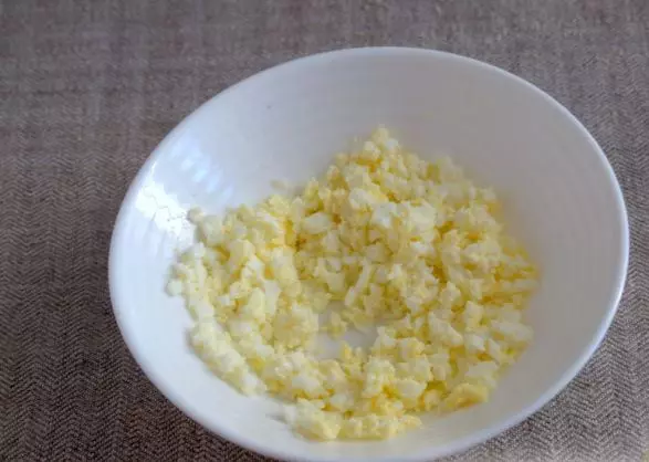 Grinding boiled eggs in white tanks on the table