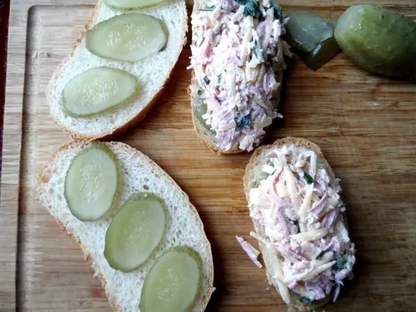 Slices of baton with marinated cucumber circles and a mixture of sausage, cheese and mayonnaise