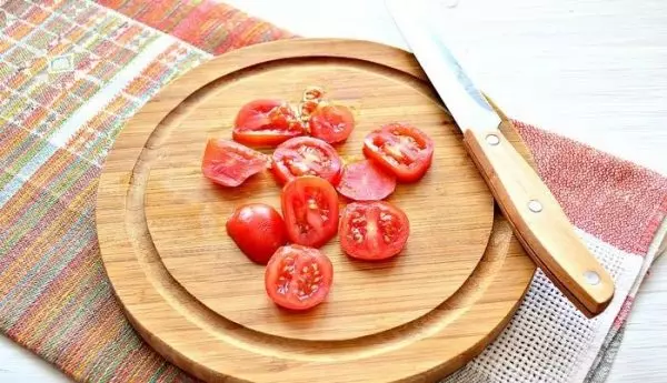 Gesneden tomaat op een houten snijplank met een mes