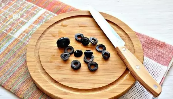 Sliced ​​olives on a wooden cutting board with a knife