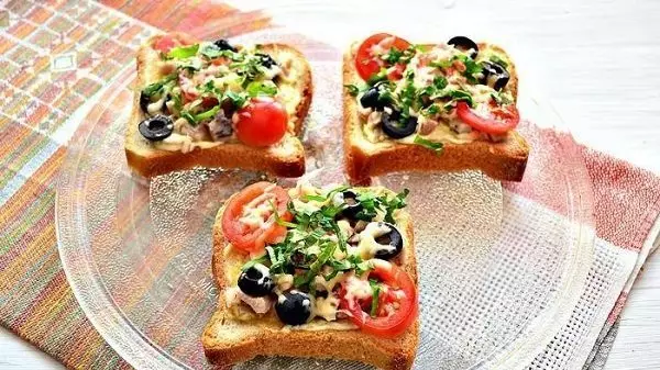 Hot chicken sandwiches, tomatoes, cheese, olives and greens on a glass plate