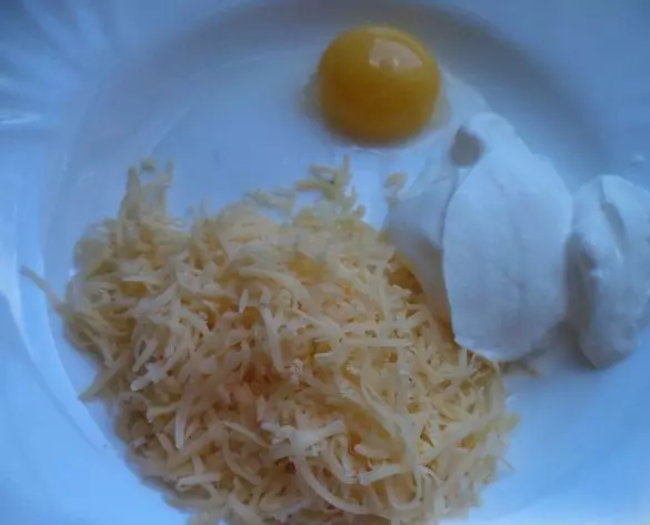 Curly hard cheese, egg yolk and sour cream on a plate