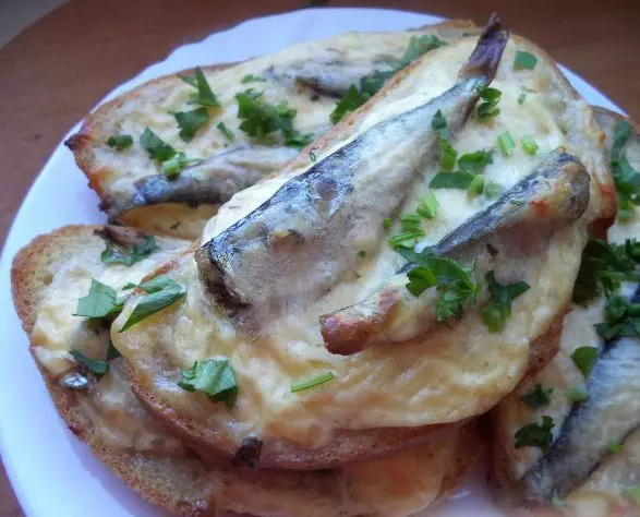 Hot sandwiches in the oven with sprats and cheese on a plate