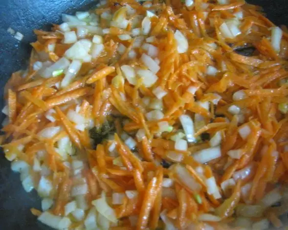 在煎鍋中計算出大型植物胡蘿蔔和切碎的洋蔥