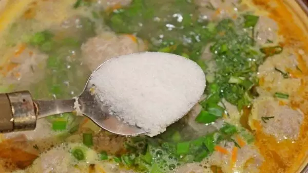 Didelis šaukštas su druska per puodą su sriuba
