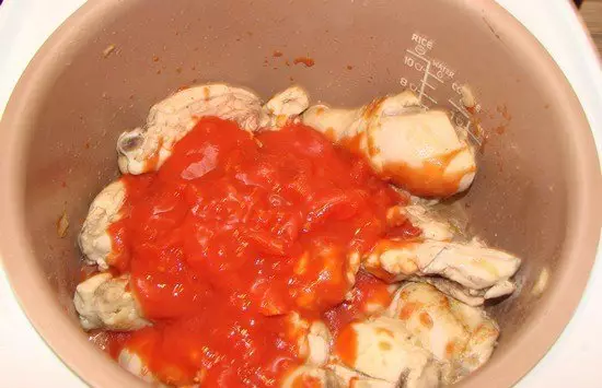 Kontserbak tomateak beren zukuan, oilasko eta tipula anitzeko katilu batean