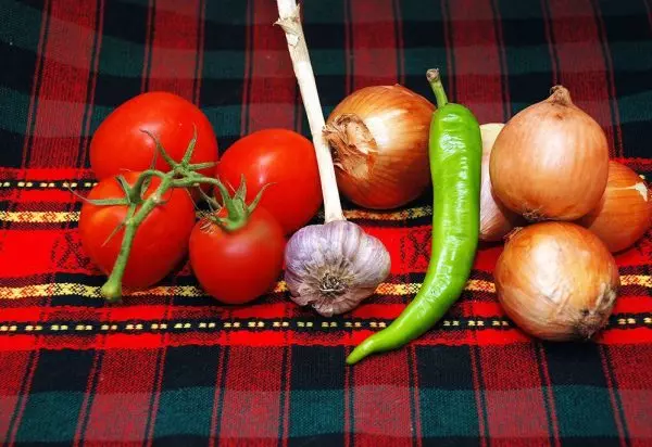 Tomates, cebollas, ajo y cápsula de pimienta aguda en la mesa