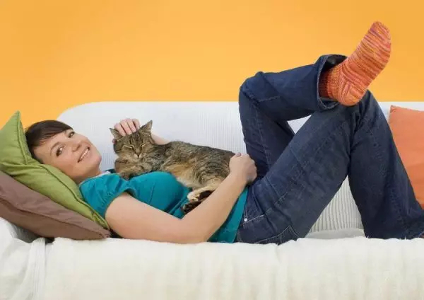 Gadis dan kucing berbaring di sofa