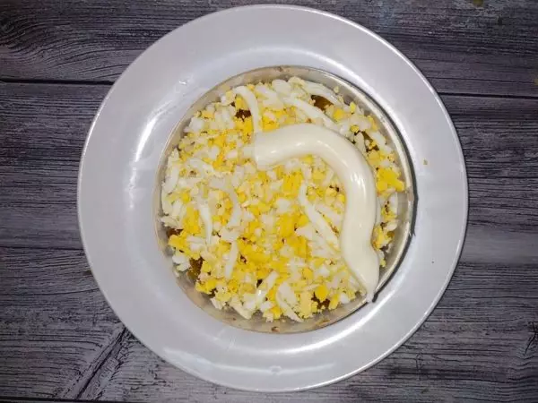 Lapisan telur rebus parut dan mayonis dalam cincin acuan logam di atas pinggan